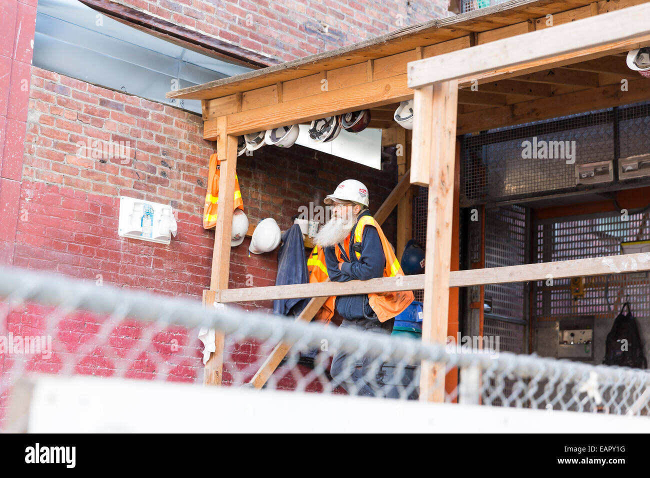 Construction worker wearing a bright orange safety vest and hard hat ...