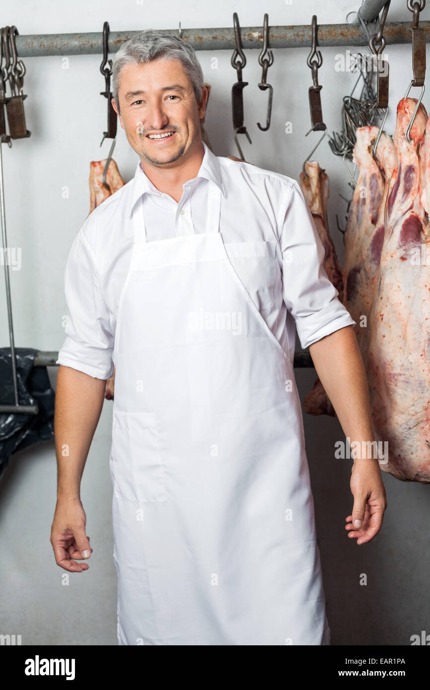 Butcher Standing Against Meat Hanging In Butchery Stock Photo - Alamy