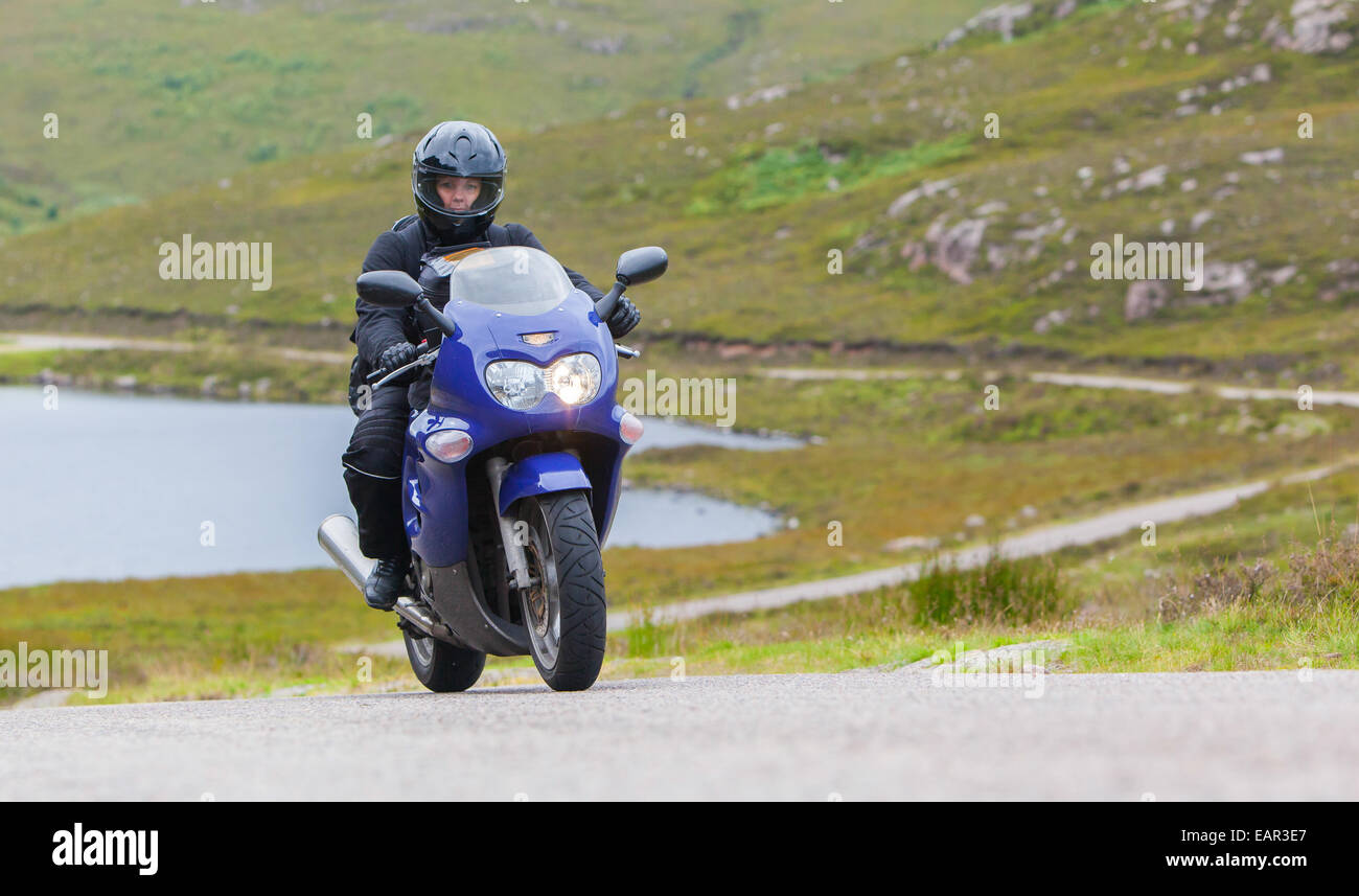Motorcyclist in the Scottish Highlands, narrow road in mountain ...