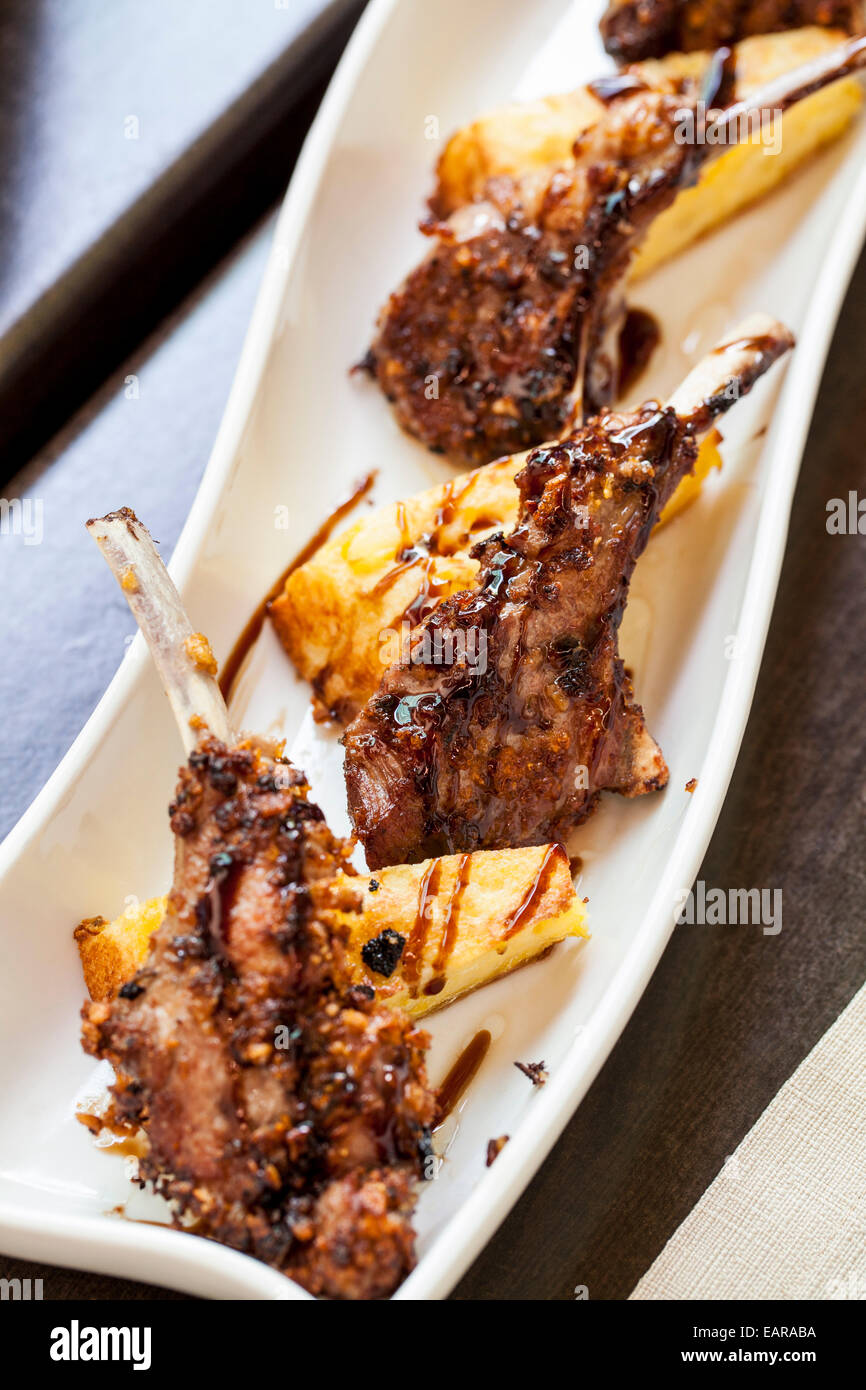 Lamb chops and tortilla pieces with a drizzled honey glaze on a platter ...