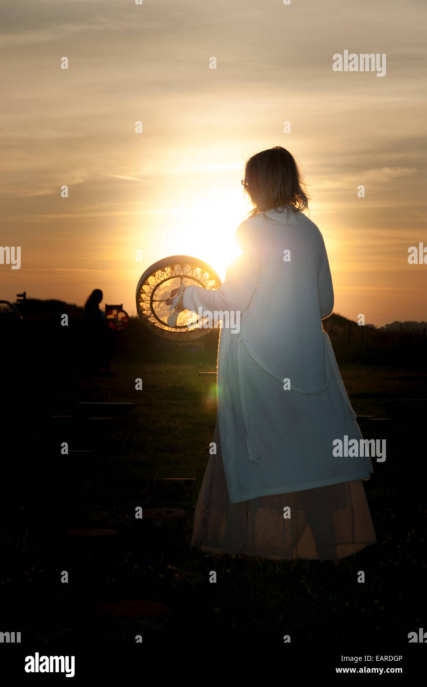 A woman drumming in the dawn a Pagan ritual at sunrise Stock Photo - Alamy