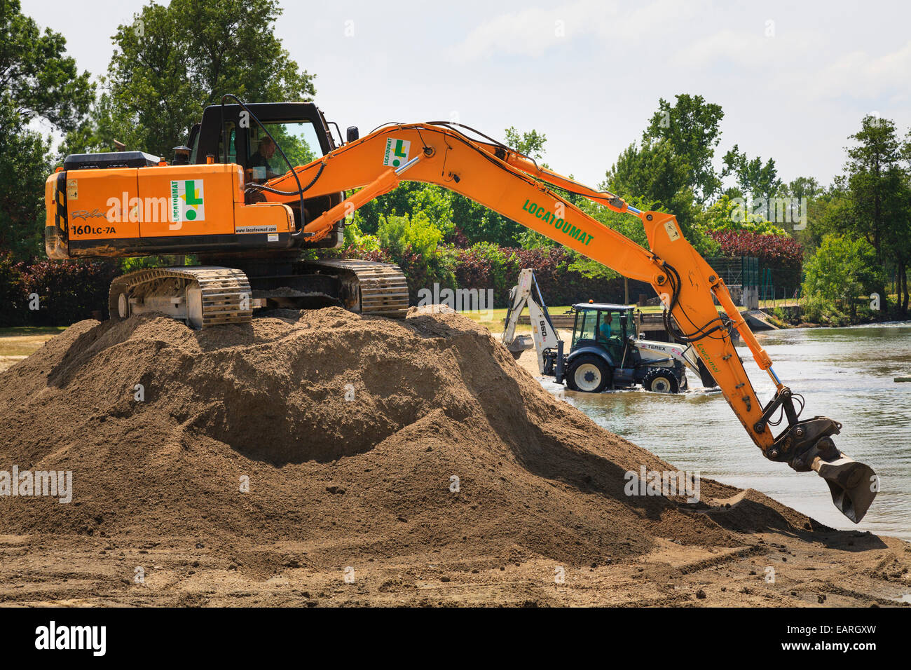 Tracked mechanical digger sitting on a pile of soil with a tractor ...