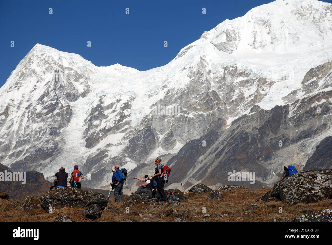 A group of trekkers stand below snowcapped Himalayan peaks in the Indian state of Sikkim Stock ...