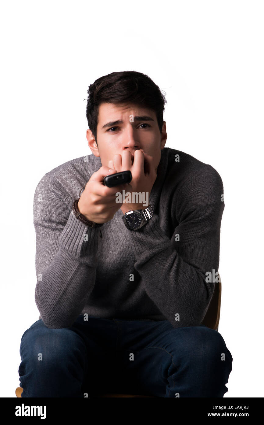 Handsome young man holding remote control and changing TV channels ...