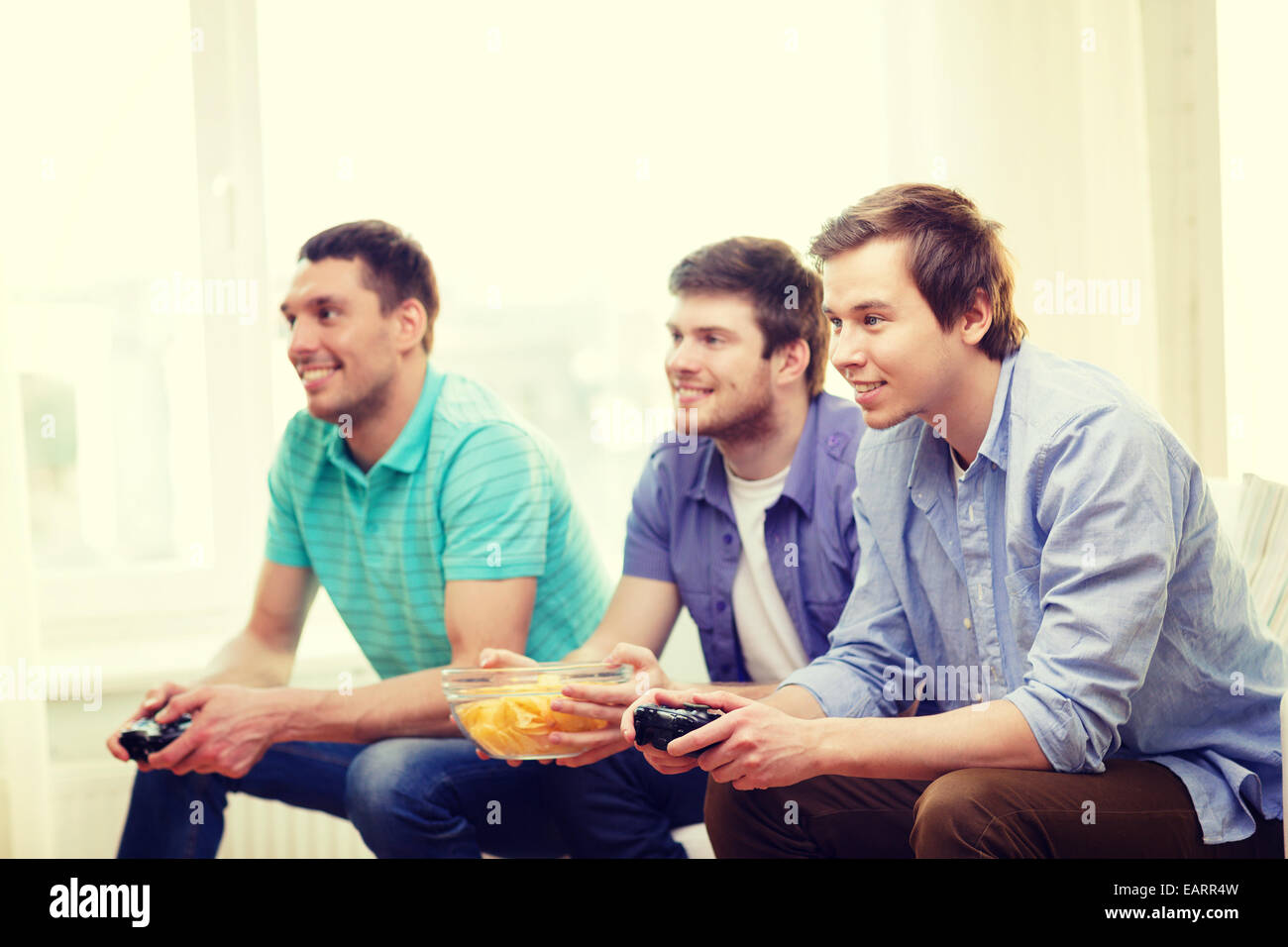 smiling friends playing video games at home Stock Photo - Alamy