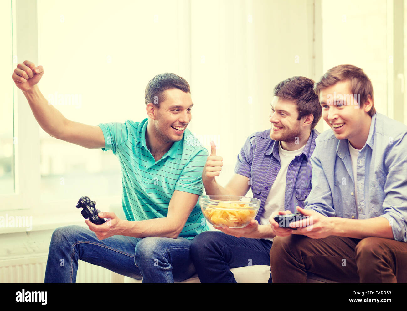 smiling friends playing video games at home Stock Photo - Alamy