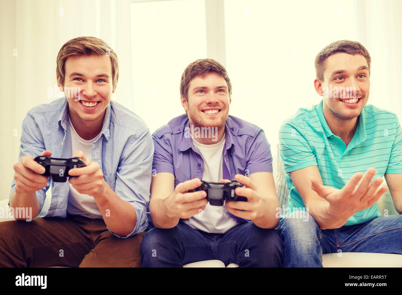 smiling friends playing video games at home Stock Photo - Alamy