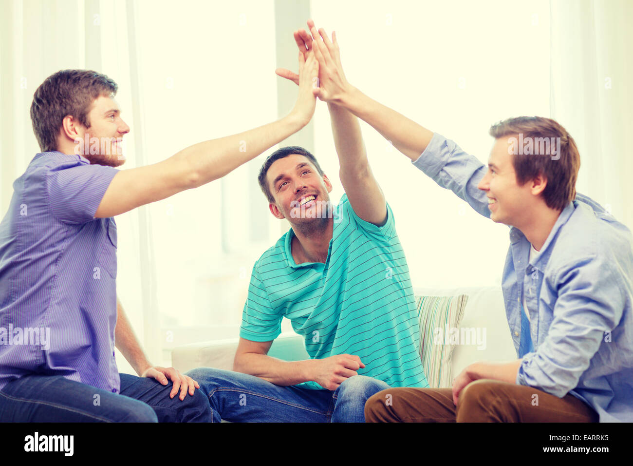 smiling male friends giving high five at home Stock Photo - Alamy