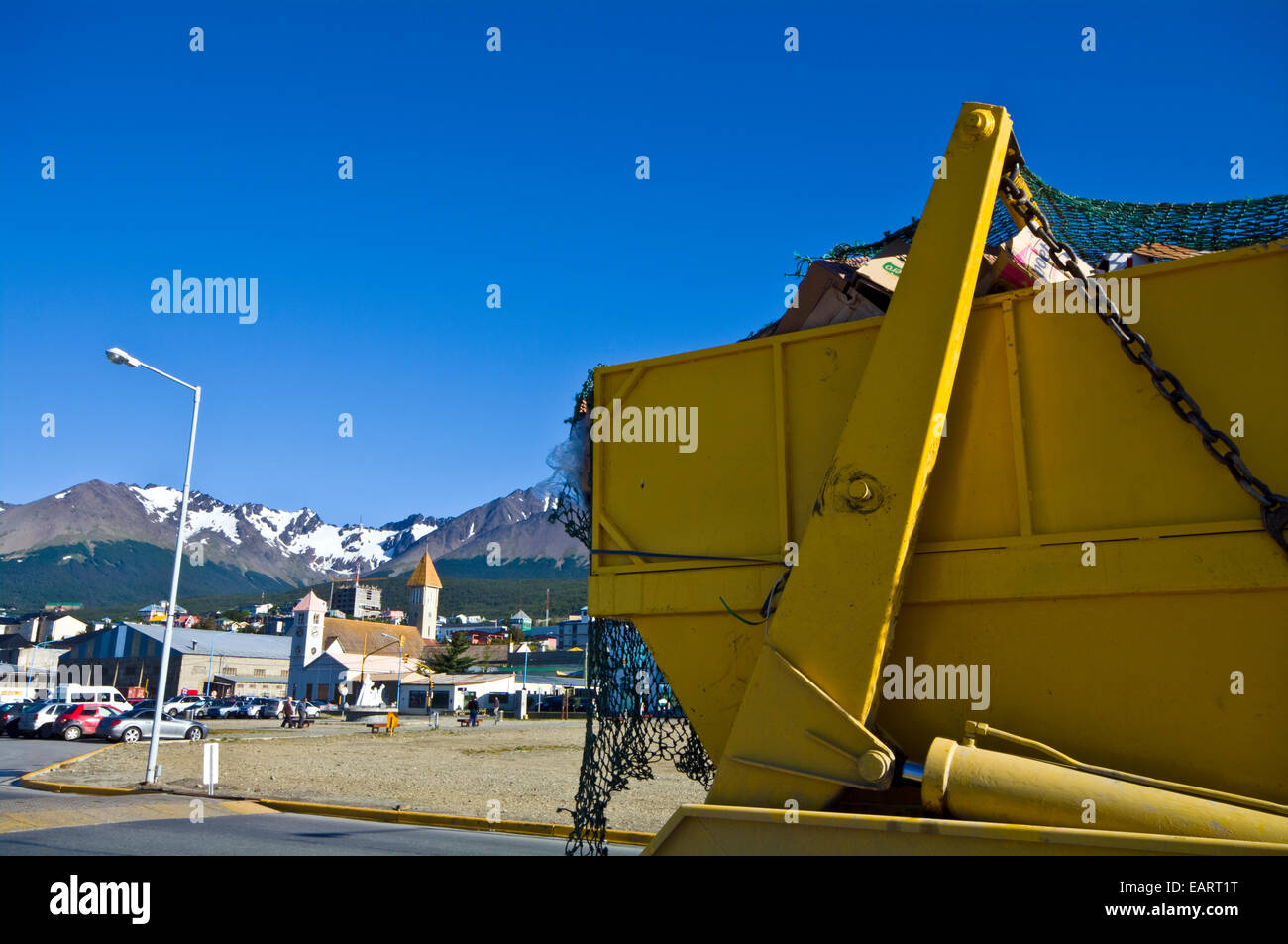 A bright yellow garbage truck beneath pristine mountains and snow Stock ...