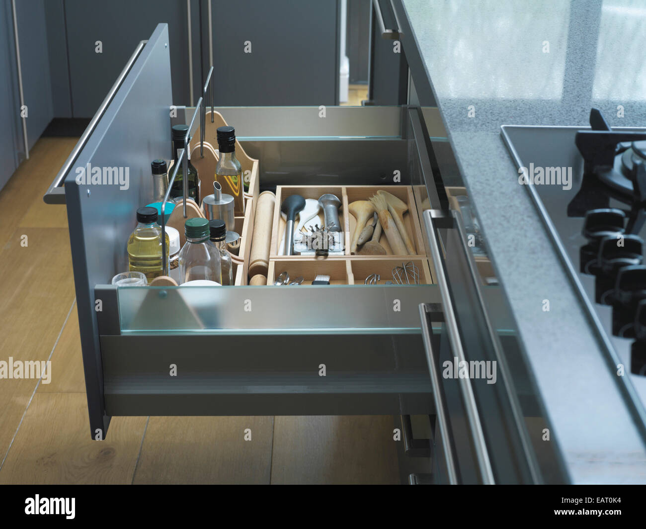 Cutlery and bottles in open drawer of kitchen unit Stock Photo - Alamy