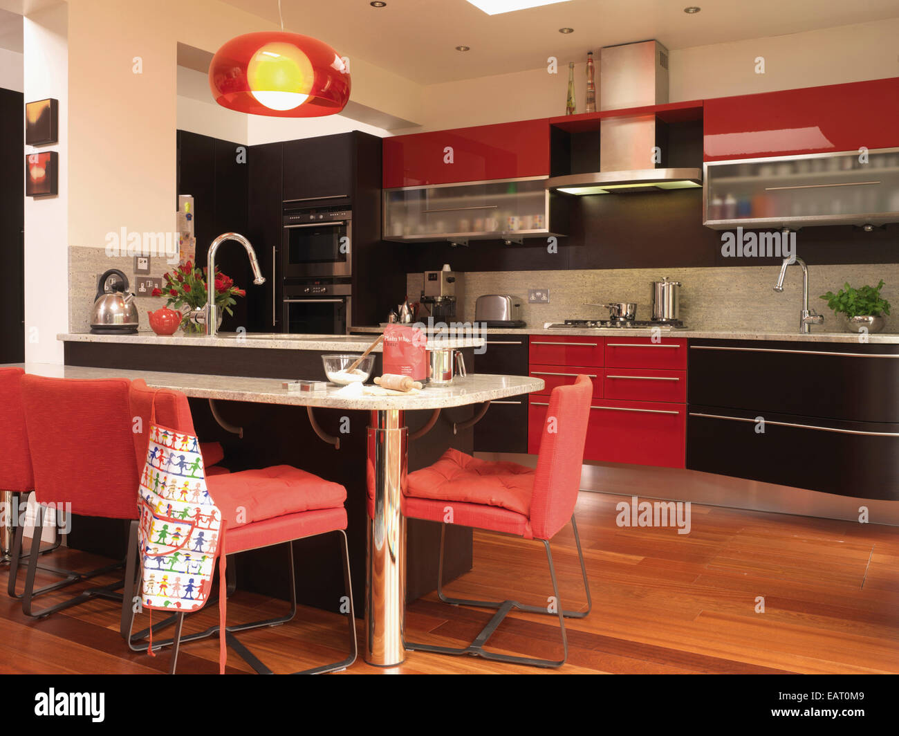Contemporary red kitchen with central breakfast bar Stock Photo - Alamy