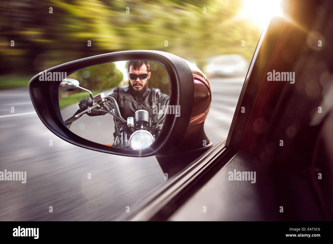 Biker in rear view mirror of the car Stock Photo - Alamy