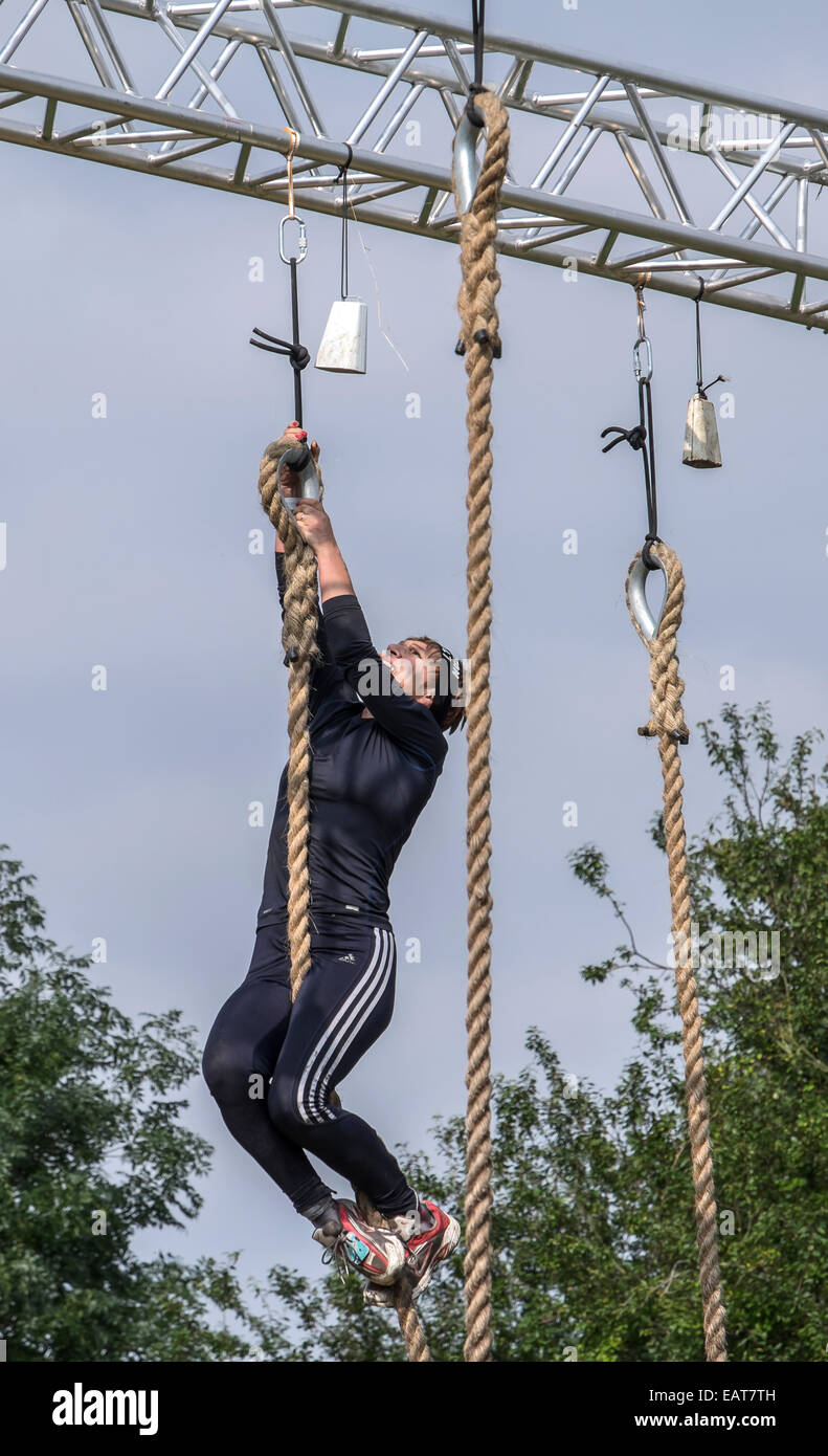 Female competitor going through pain barrier on rope obstacle at ...