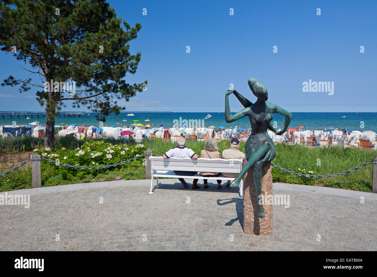 Tourists sitting on bench and looking over the beach at Timmendorfer ...