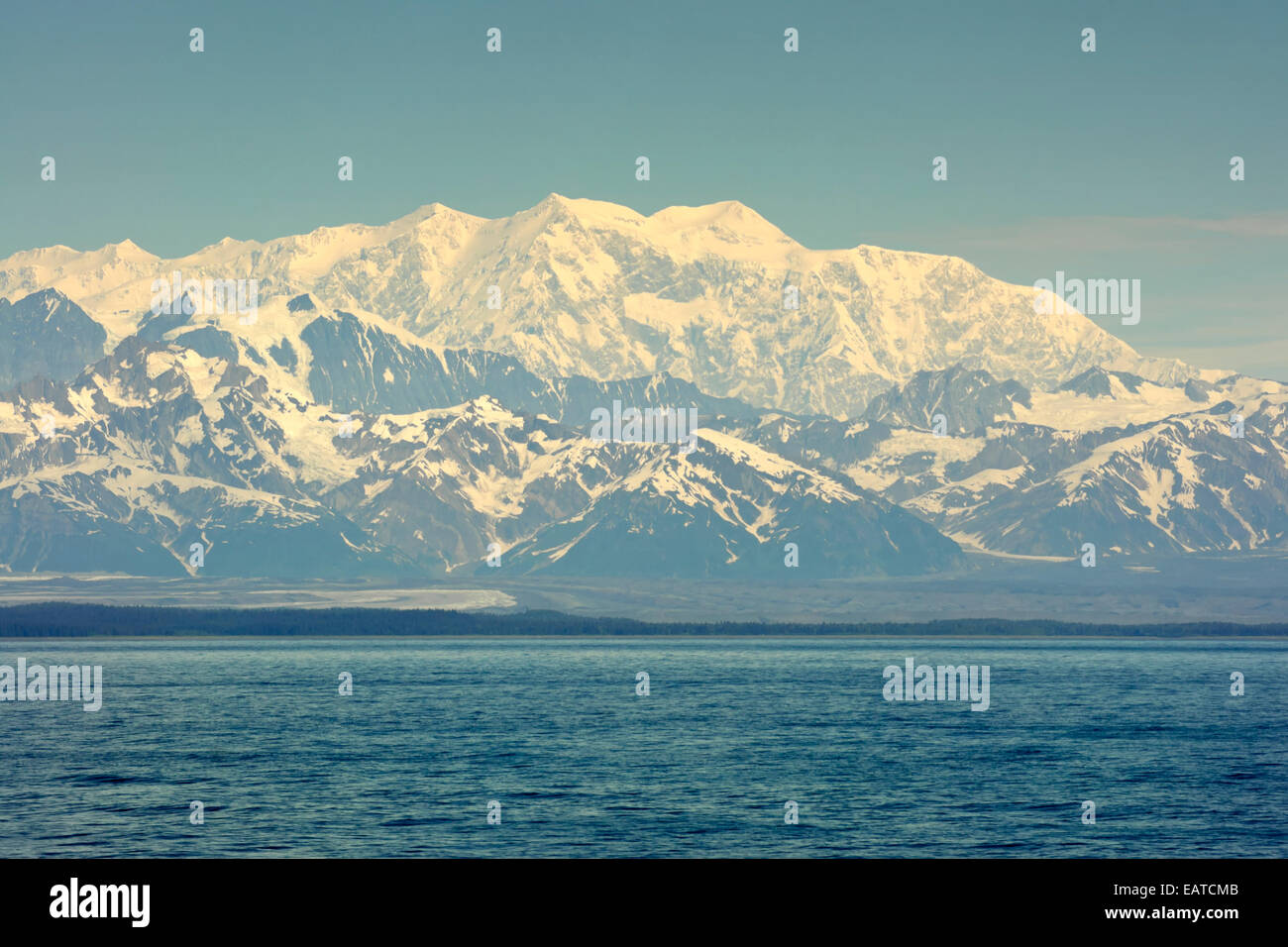 Snow covered mountains tower over the west coastal plain of Alaska ...