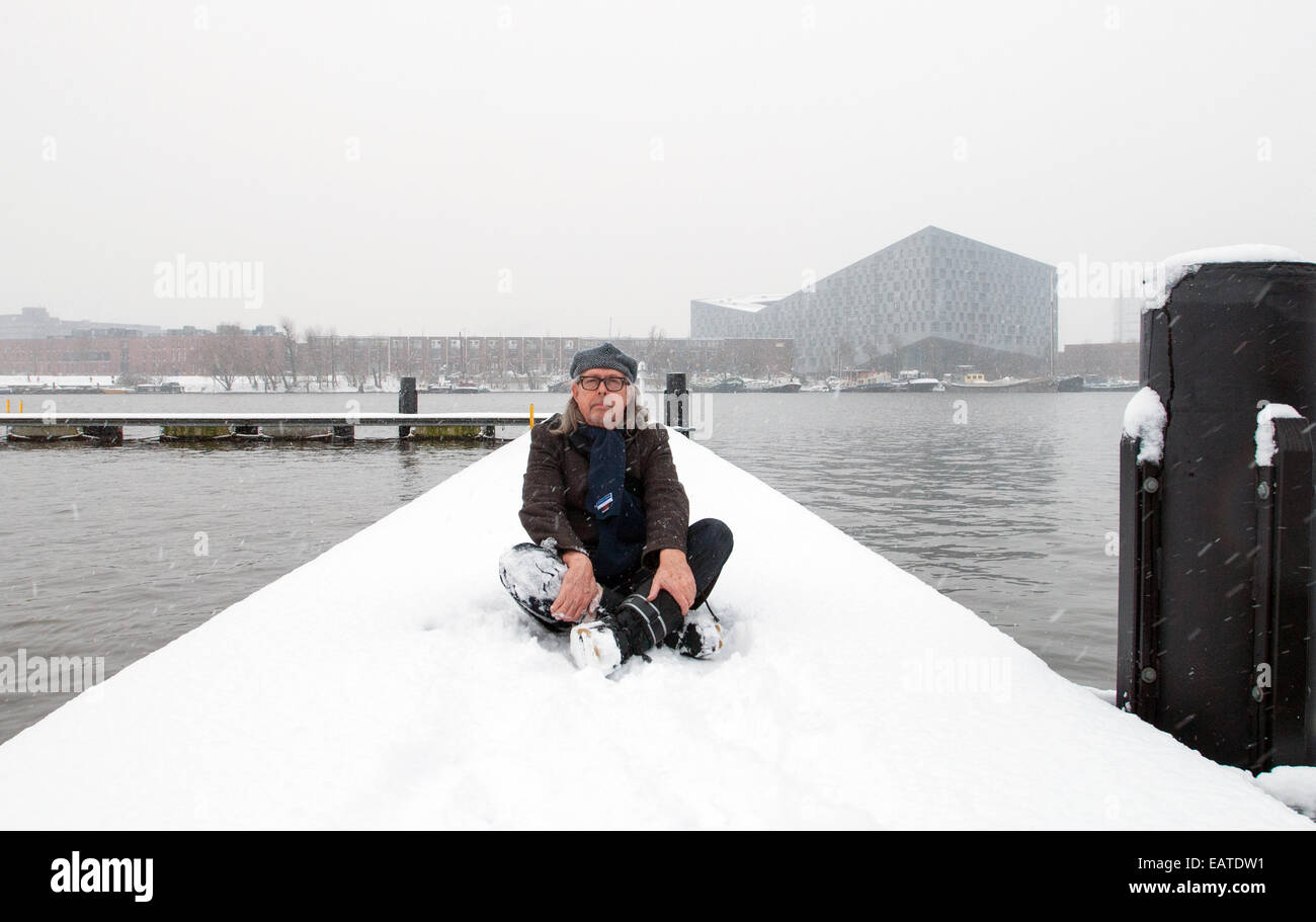 Man sitting in fresh snow on a pier in the Amsterdam Harbor Stock Photo ...
