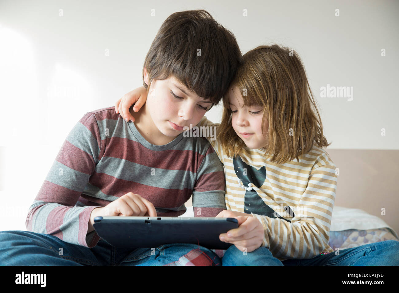 Children playing with a digital tablet on the bed Stock Photo - Alamy