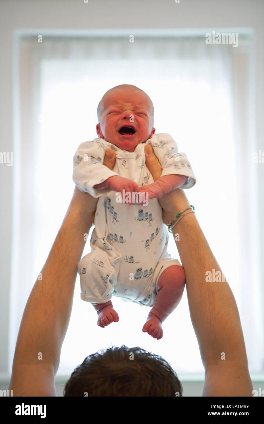 Parent holding up a crying baby Stock Photo - Alamy