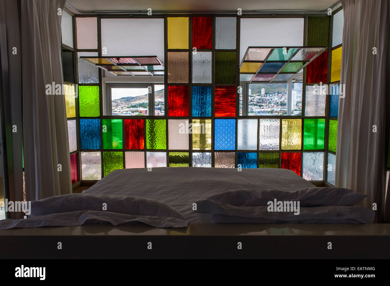 A colorful stained glass window wall surrounding an apartment bedroom ...