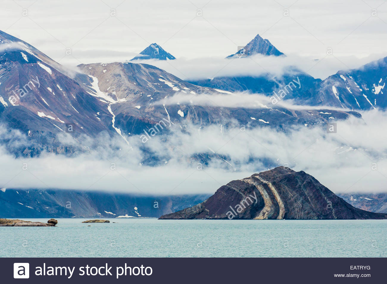 An island of folded rock sits at the base of a mountain range Stock ...