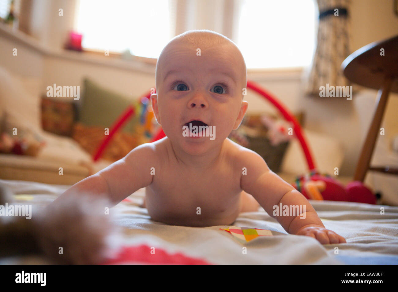 Baby propping himself up on arms on play mat Stock Photo - Alamy