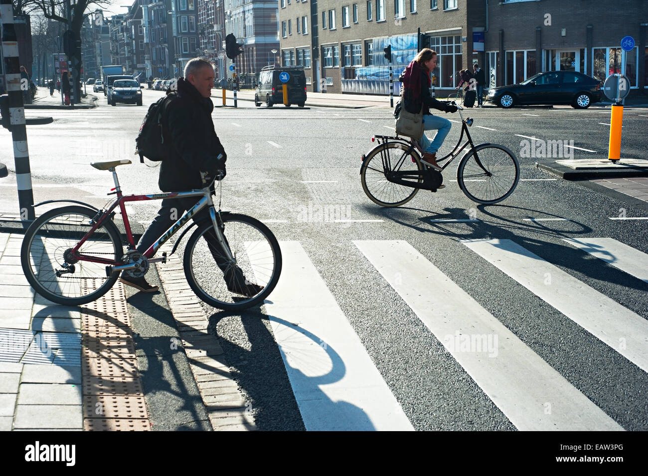 Unidentified people crossing the street by bicycle in Amsterdam. It is ...