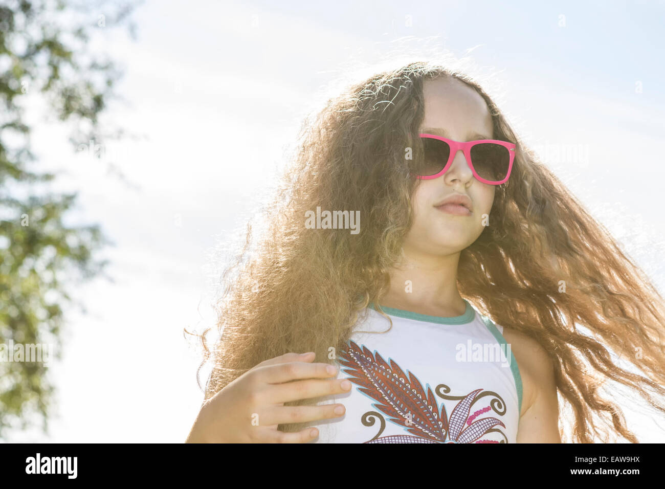 Young girl in sunglasses fixing her long blond hair in the sunlight on ...