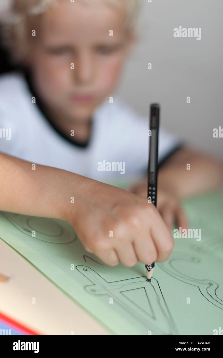 a 7-year old schoolchild is doing writing exercises as homework for ...