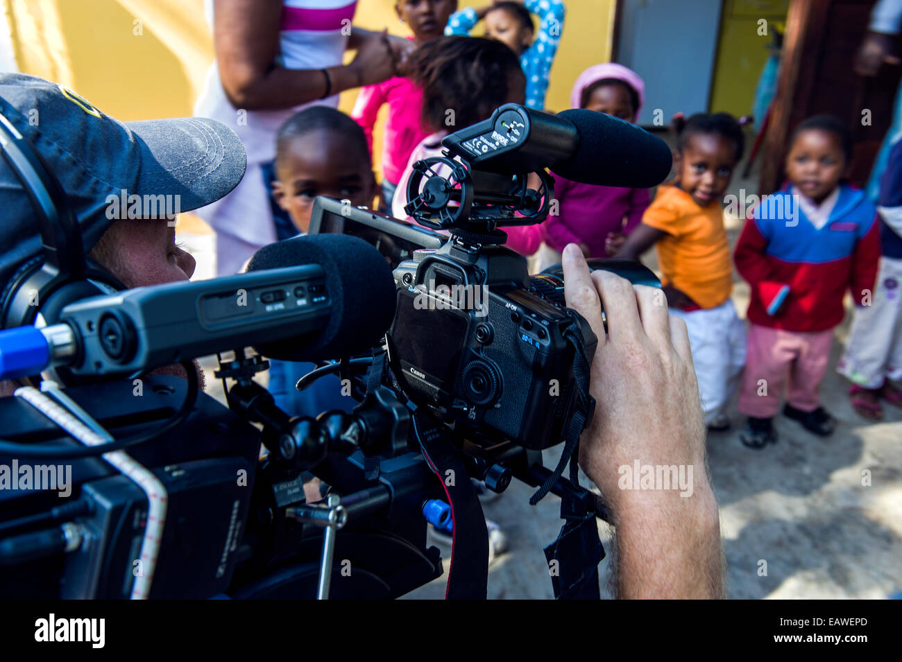 A cameraman filming African refugee children playing at a pre-school ...