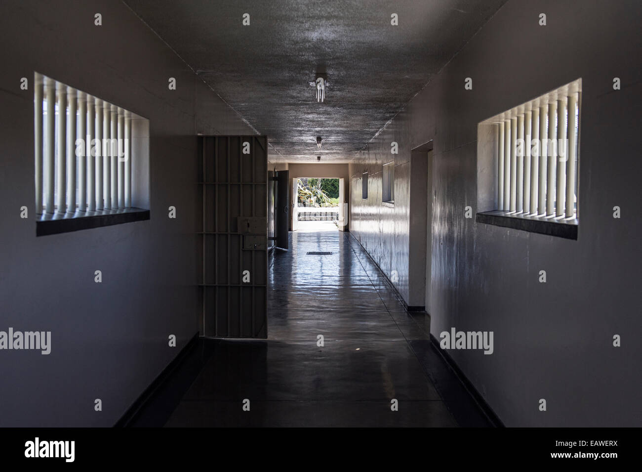 Austere prison corridor with polished concrete floor and window bars ...