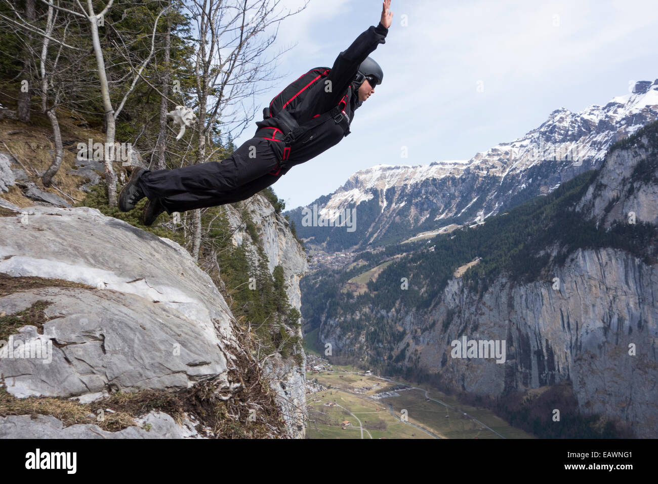BASE jumper is exiting from a cliff down into the deep valley. Thereby ...