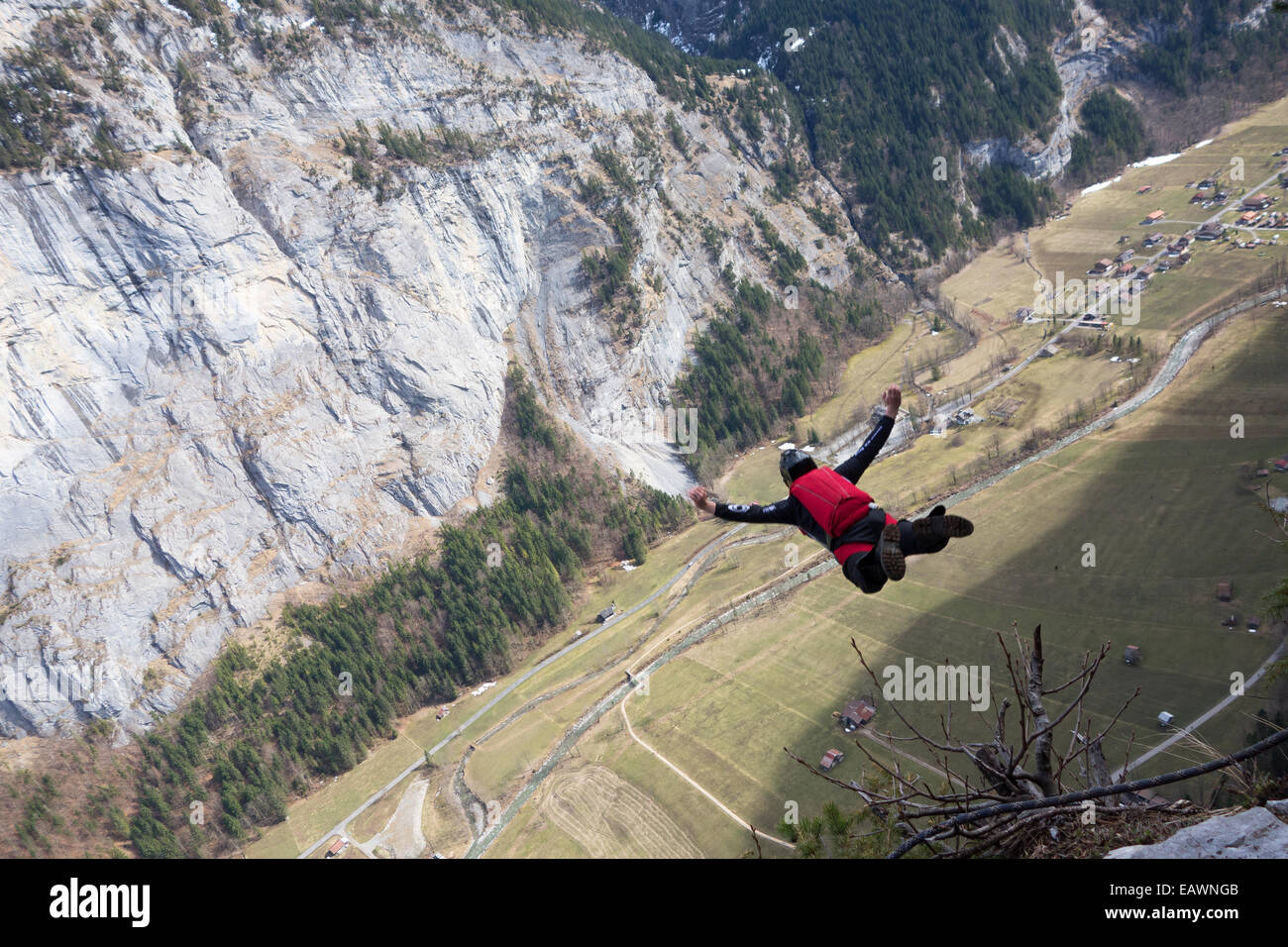 BASE jumper is exiting from a cliff down into the deep valley. Thereby ...