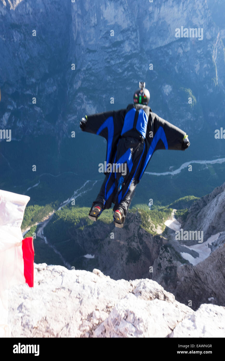 BASE jumper is exiting from a cliff down into the deep valley. Thereby ...