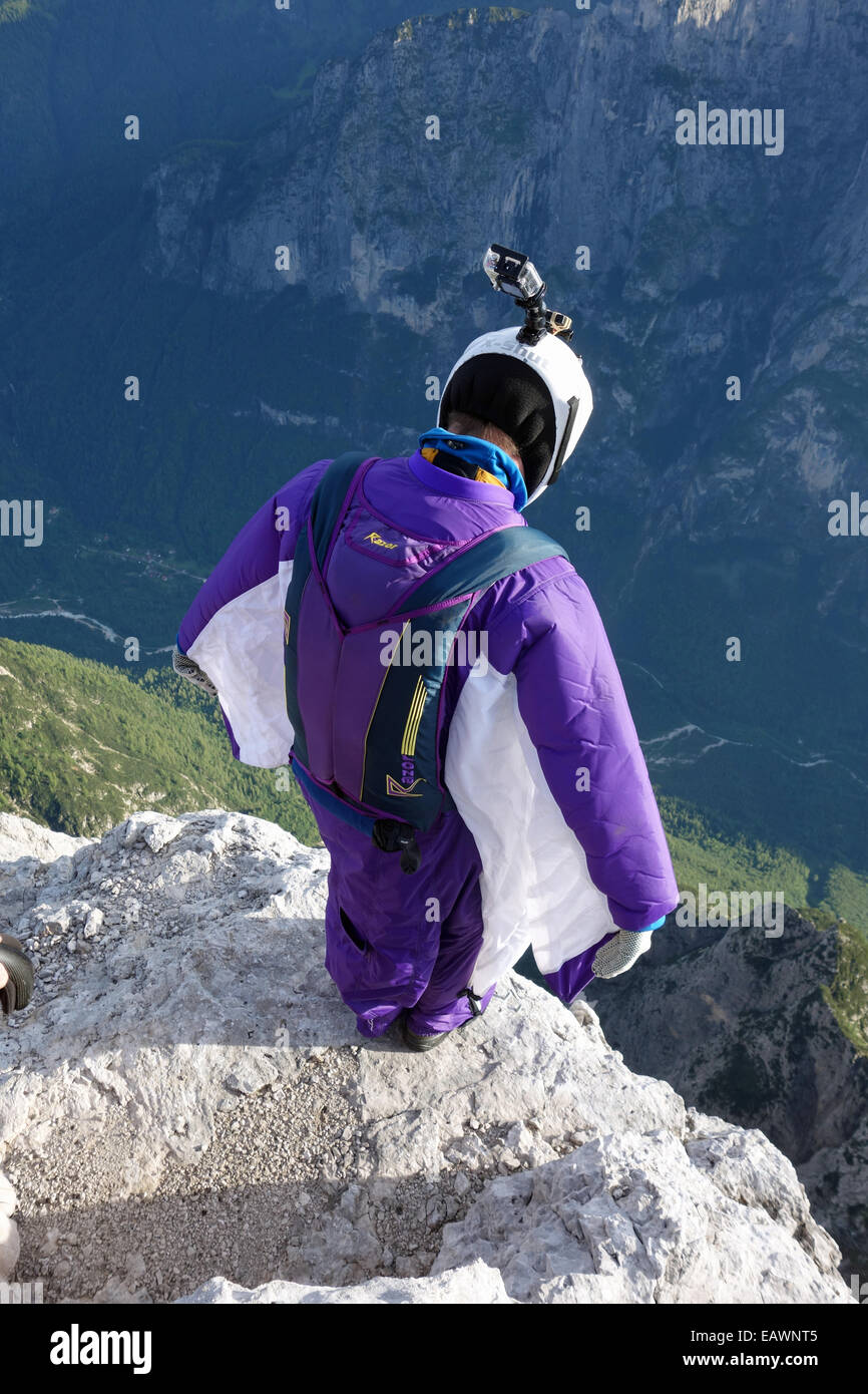 BASE jumper is exiting from a cliff down into the deep valley. Thereby ...