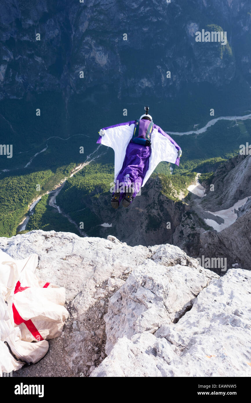 BASE jumper is exiting from a cliff down into the deep valley. Thereby ...