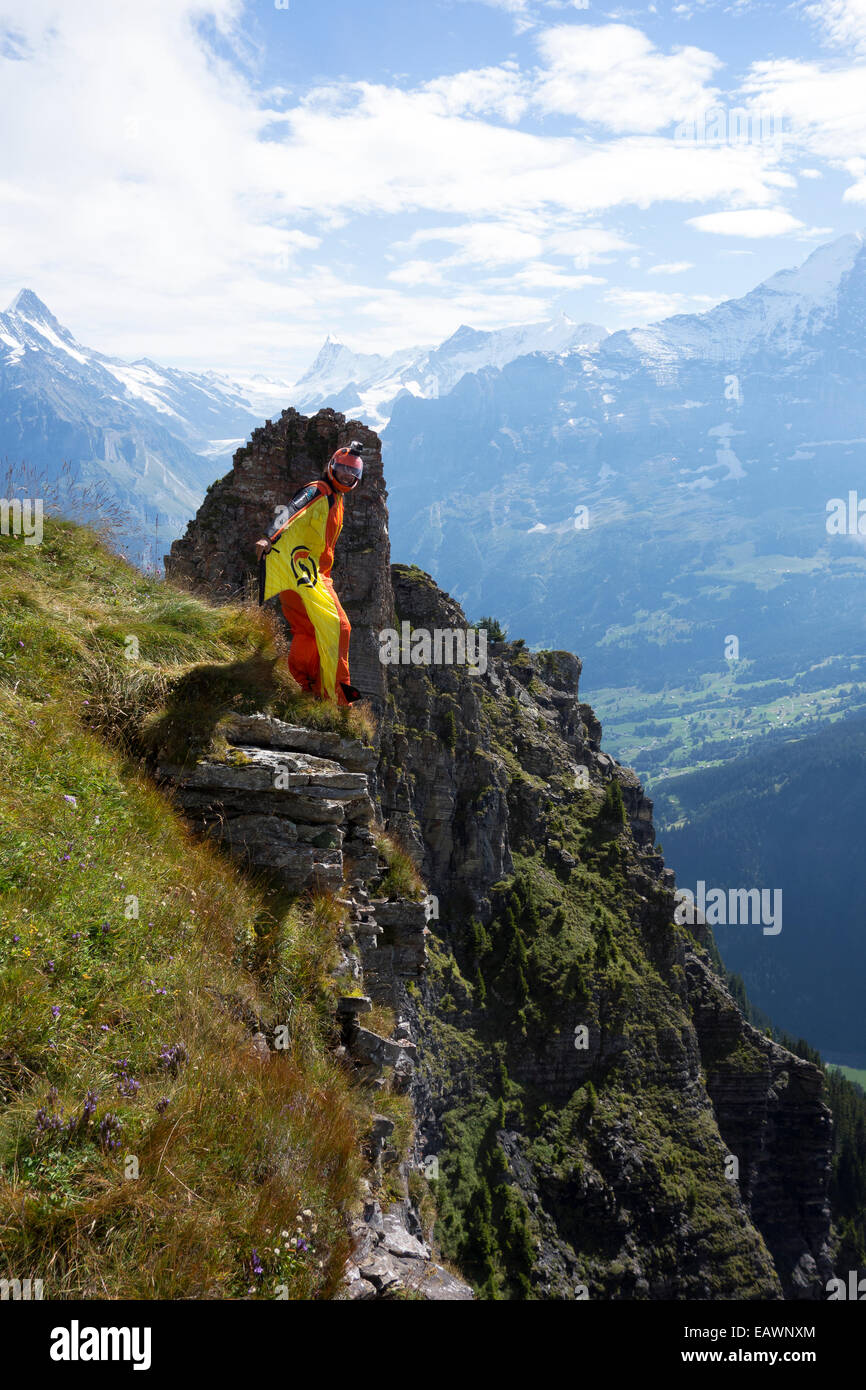 BASE jumper is exiting from a cliff down into the deep valley. Thereby ...