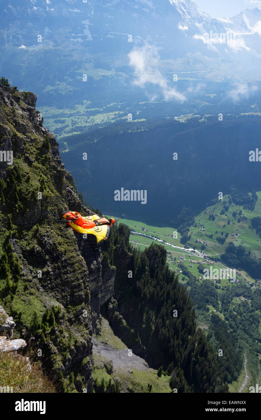 BASE jumper is exiting from a cliff down into the deep valley. Thereby ...