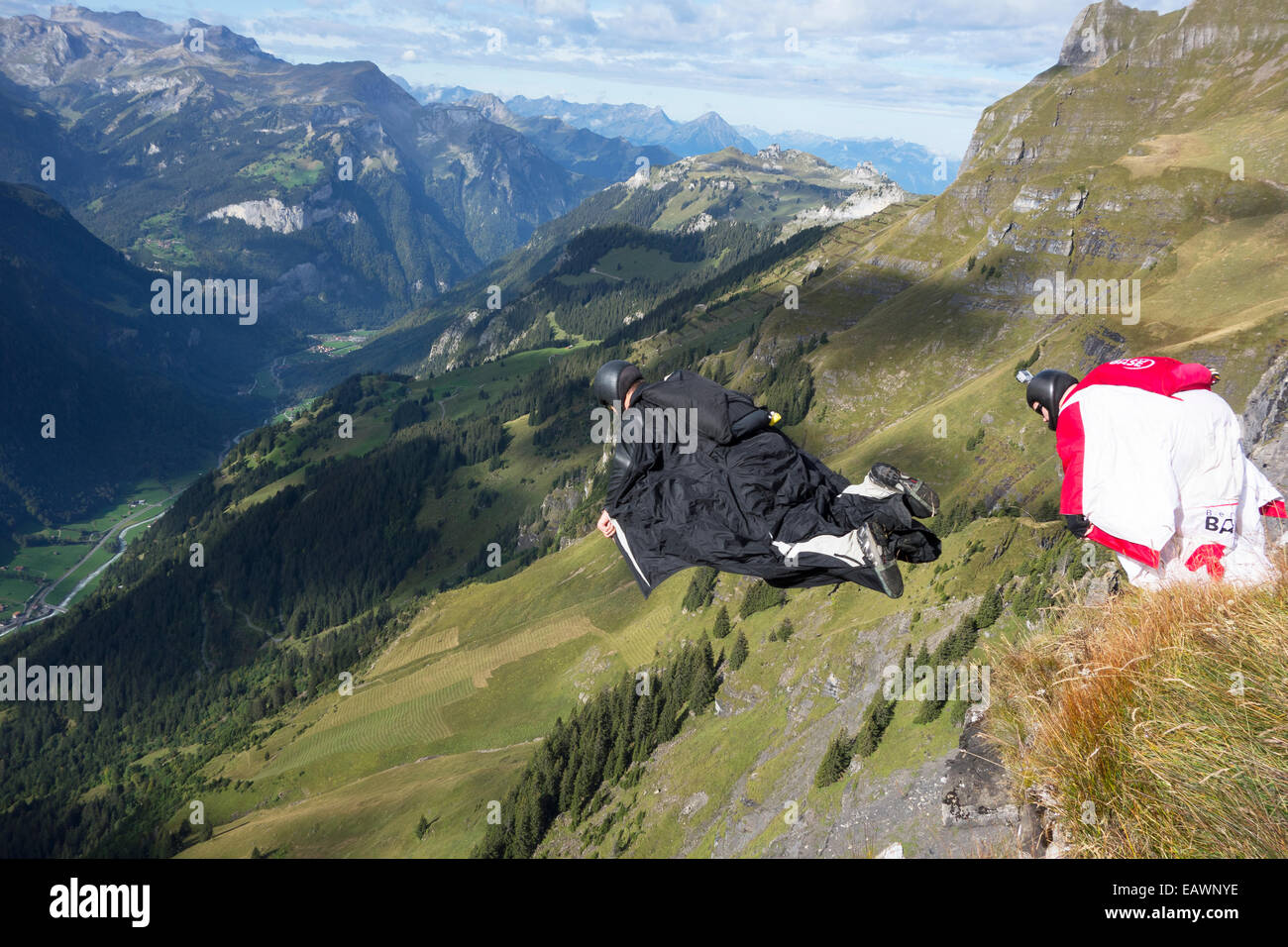 BASE jumper is exiting from a cliff down into the deep valley. Thereby ...