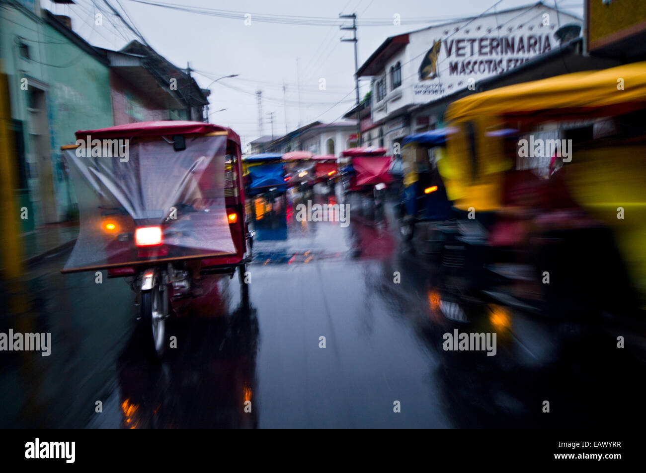 Traffic headlights swirl past an auto rickshaw on a rainy night in an ...
