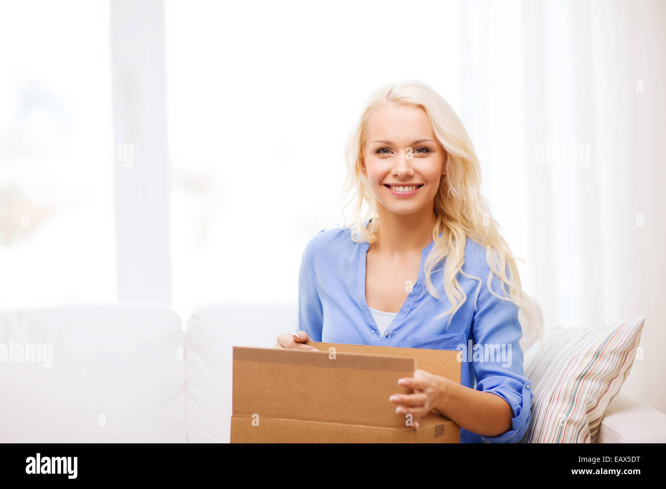 smiling young woman opening cardboard box Stock Photo - Alamy