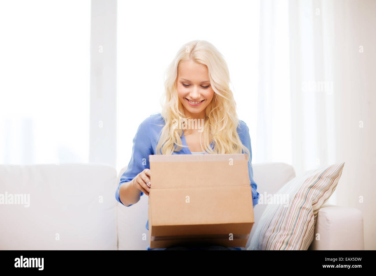 smiling young woman opening cardboard box Stock Photo - Alamy