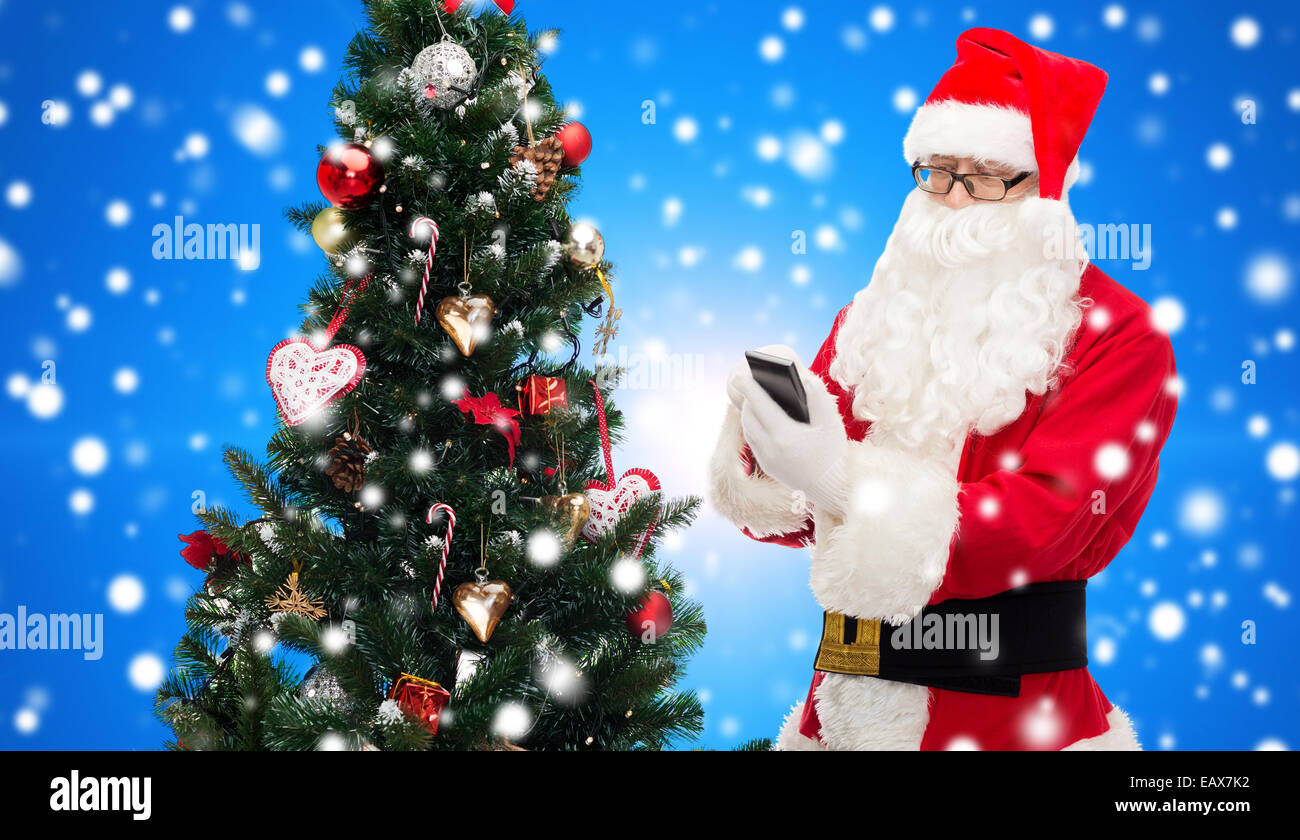 santa claus with smartphone and christmas tree Stock Photo - Alamy