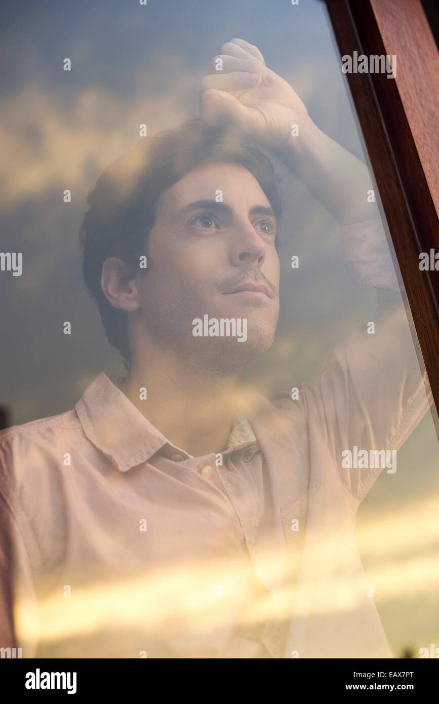 Man looking out hotel window at sunset Stock Photo - Alamy
