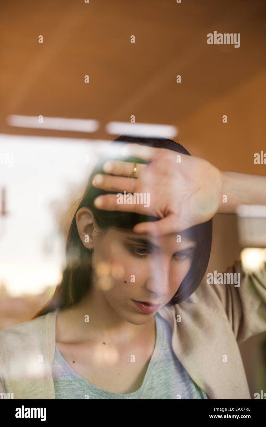 Woman leaning against window looking down Stock Photo - Alamy