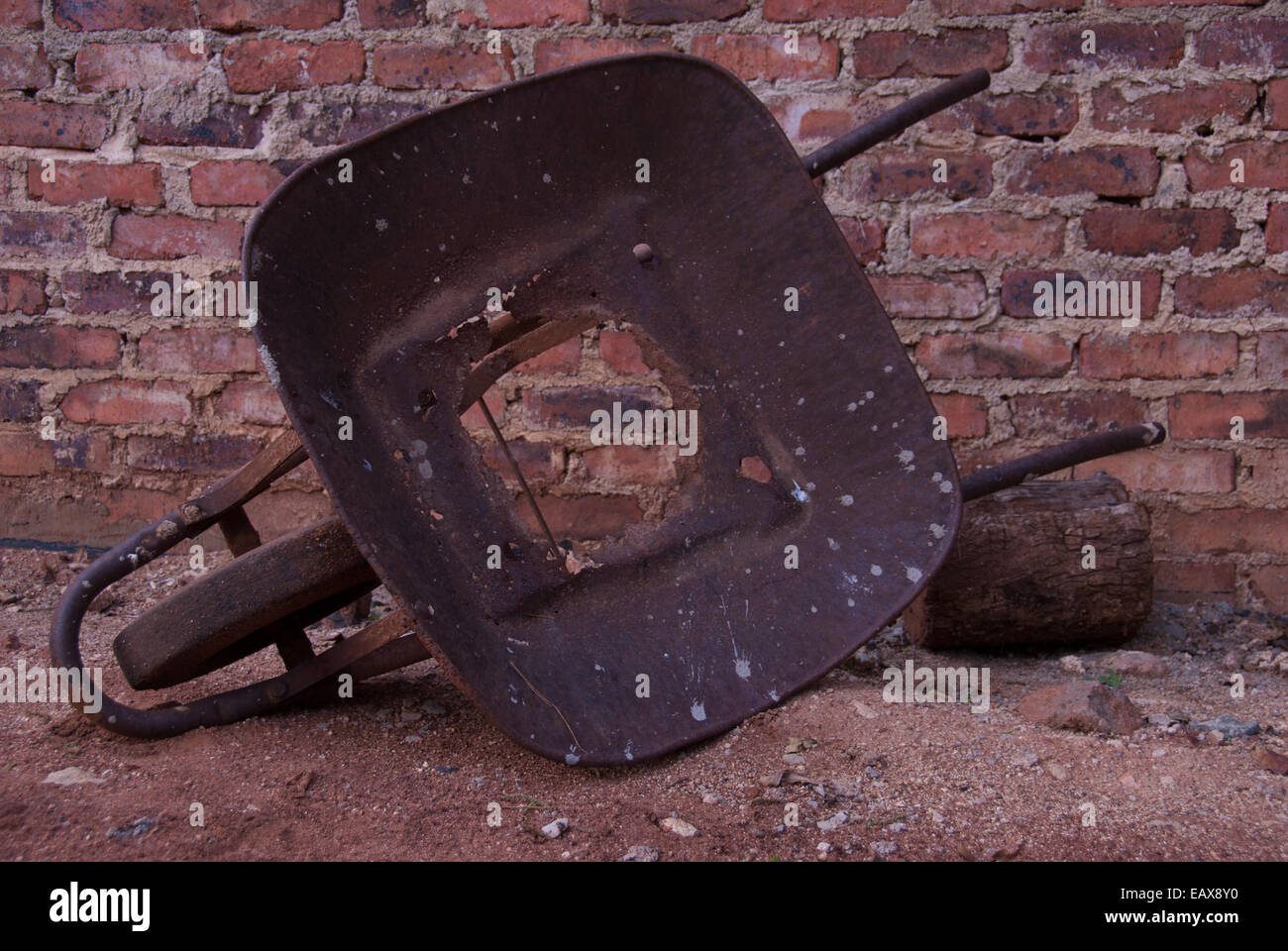 Old broken rusted wheelbarrow against a brick wall Stock Photo - Alamy