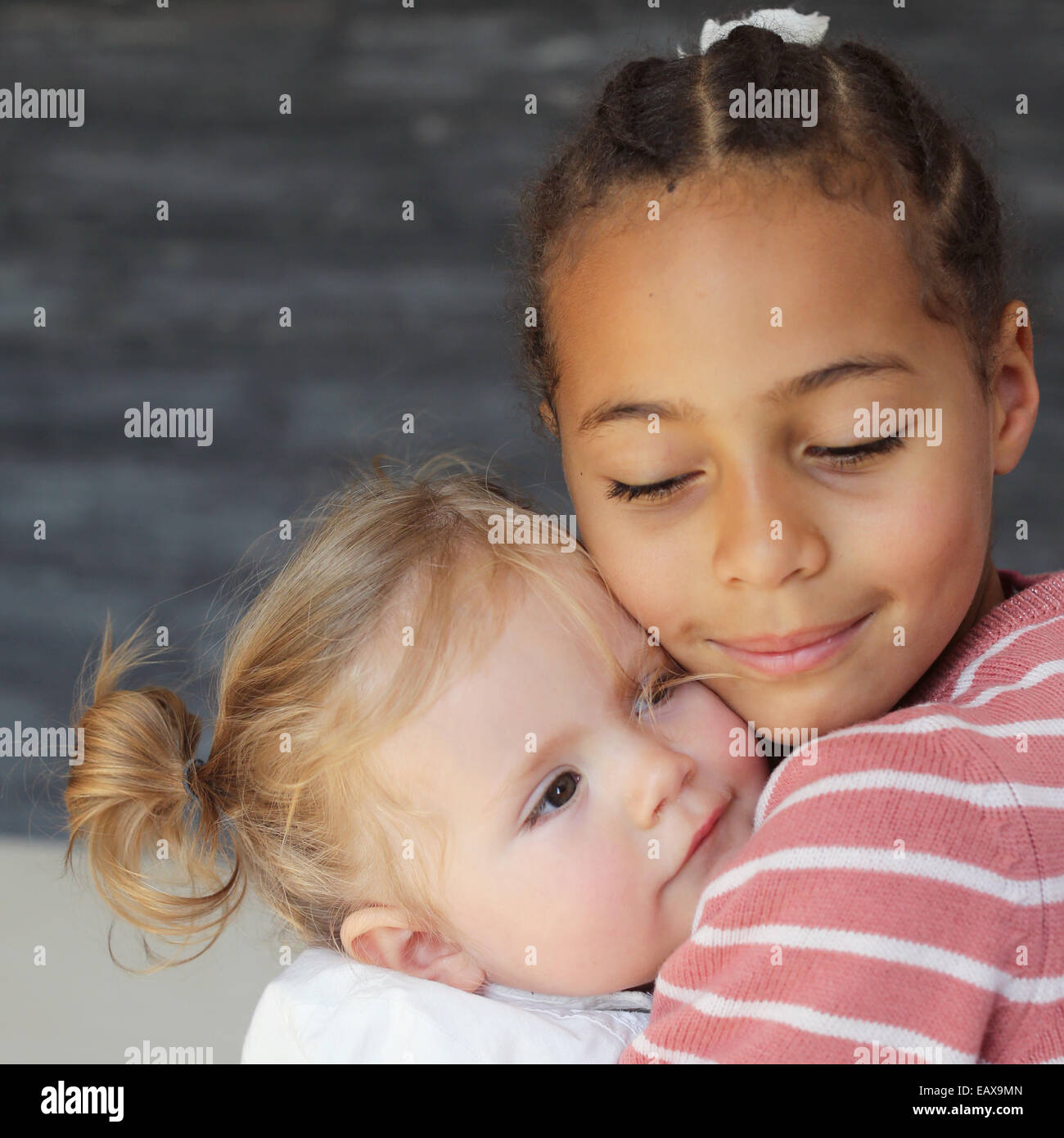 Girl embracing baby girl Stock Photo - Alamy