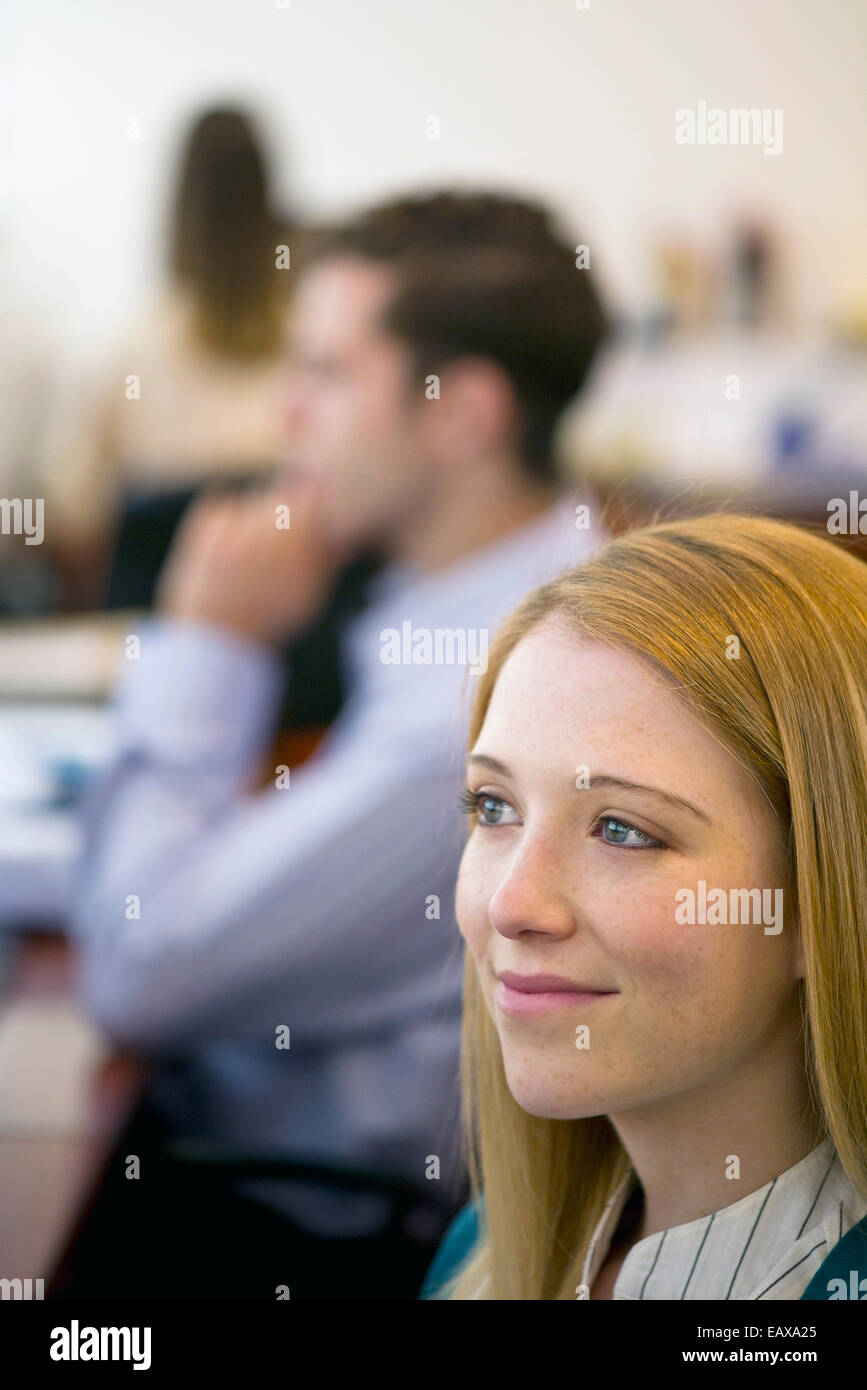 Young woman smiling dreamily in office Stock Photo - Alamy