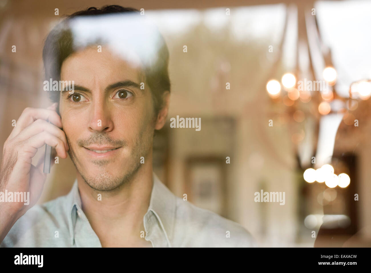 Man using cell phone looking out window Stock Photo - Alamy