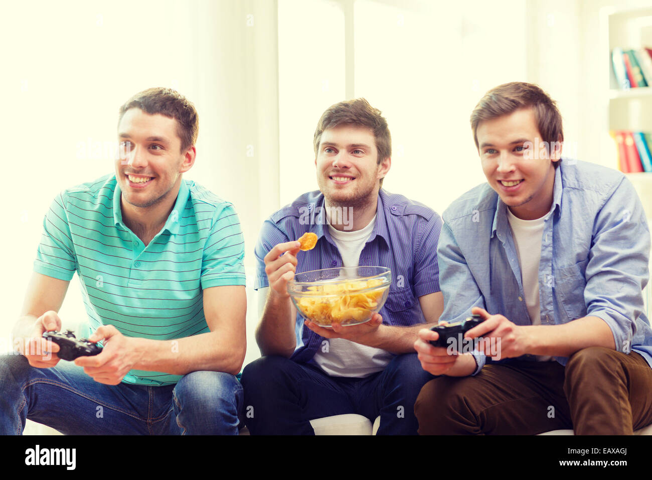 smiling friends playing video games at home Stock Photo - Alamy