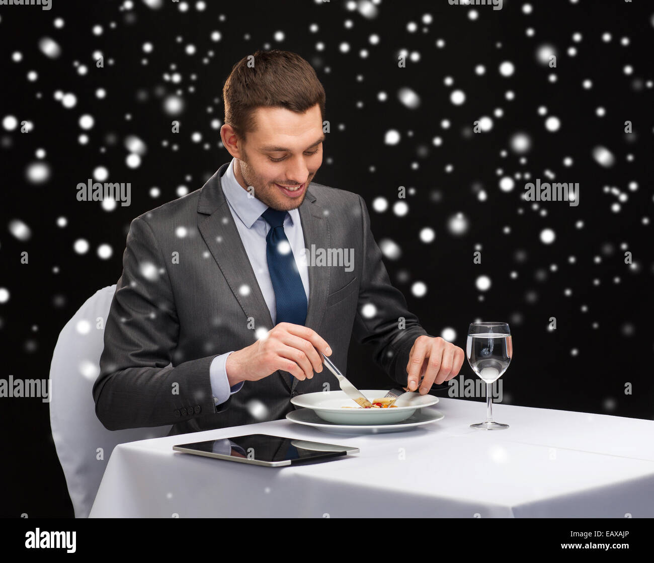 smiling man with tablet pc eating main course Stock Photo - Alamy